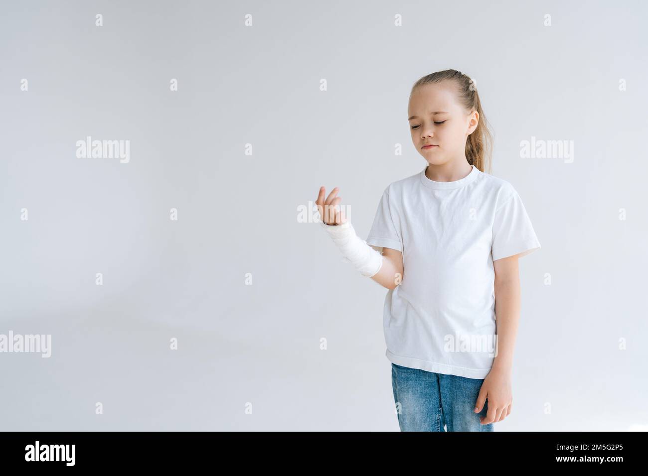 Portrait of suffering little girl with broken hand wrapped in white ...
