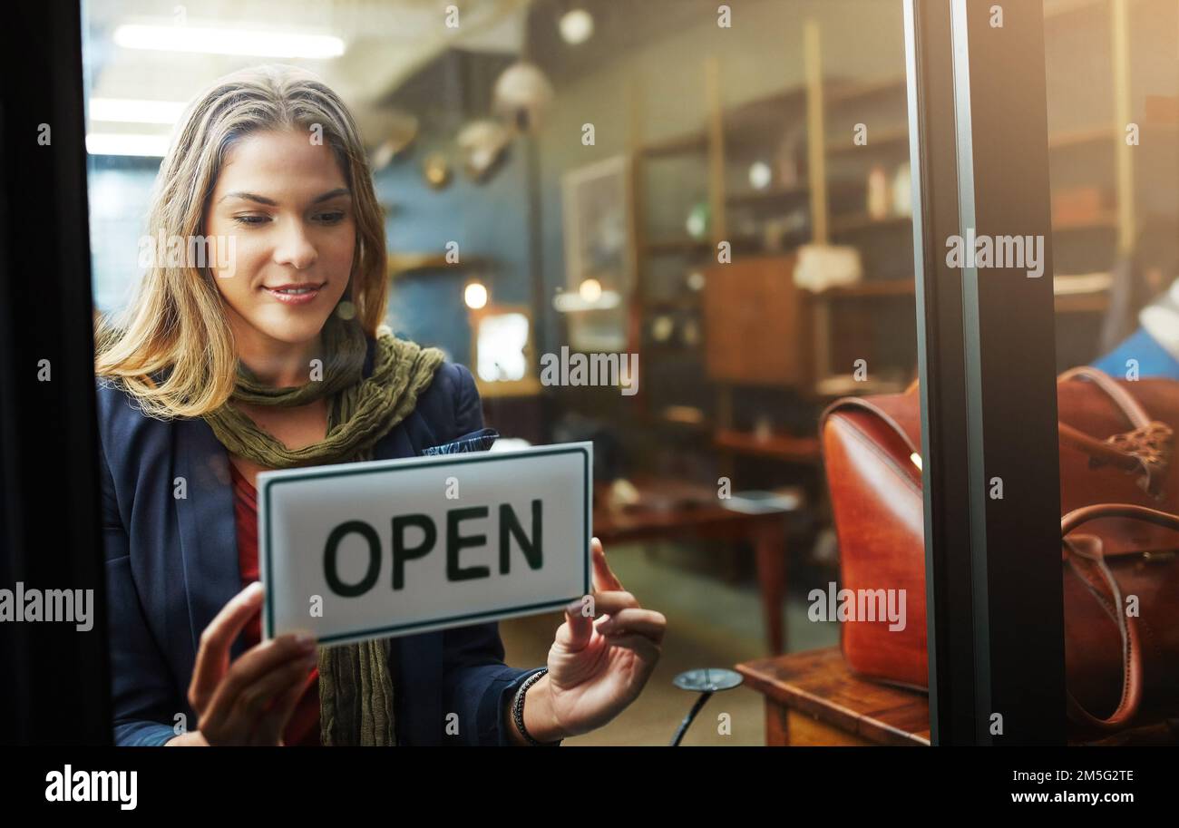 Open and ready to welcome all. a young business owner hanging up an ...