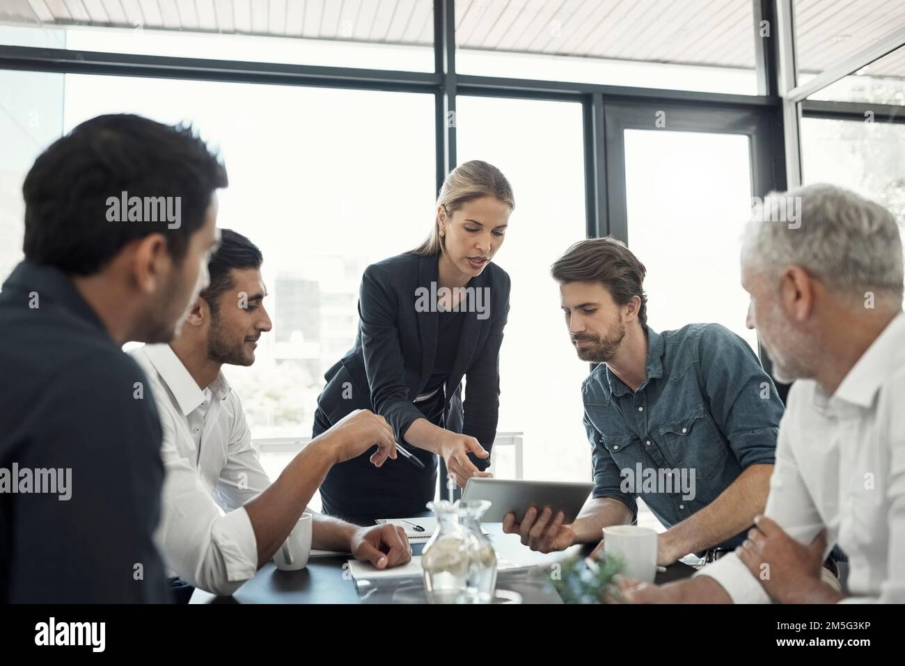 Getting down to business. a businesswoman talking to colleagues sitting ...