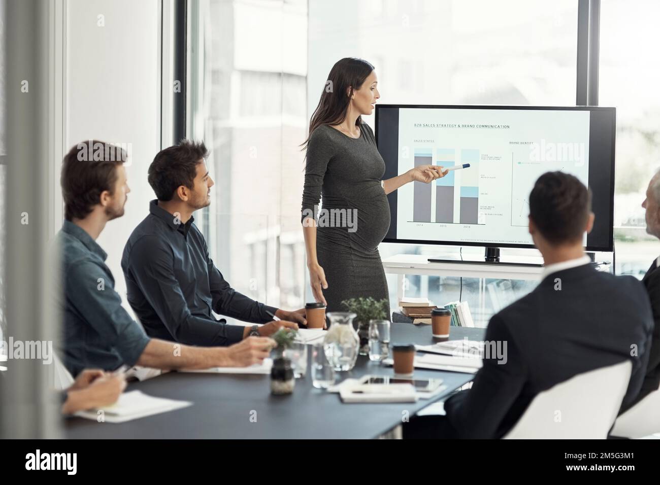 Walking her colleagues through the numbers. a pregnant businesswoman ...