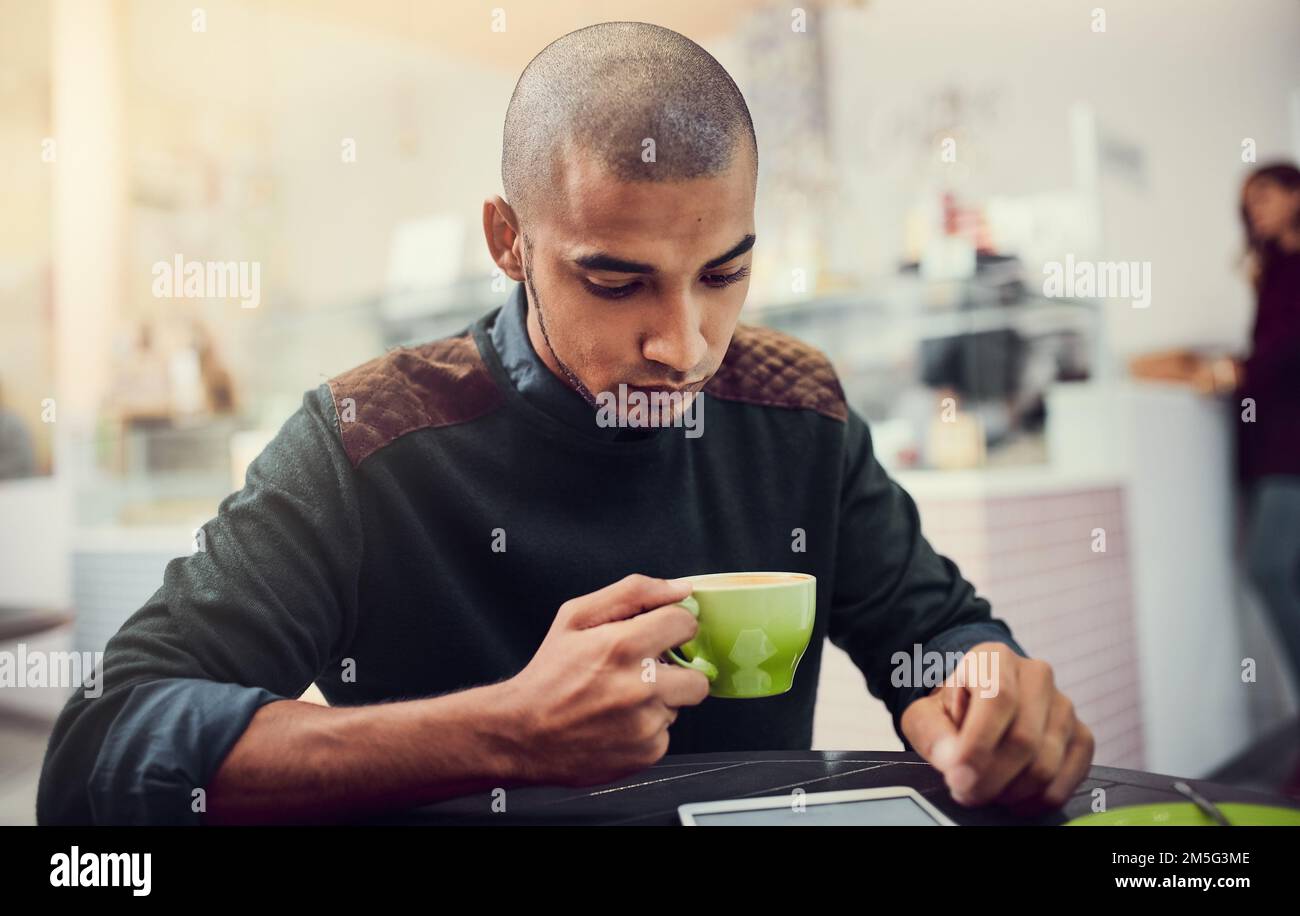 But first, coffee. a young man sitting in a cafe with his digital ...