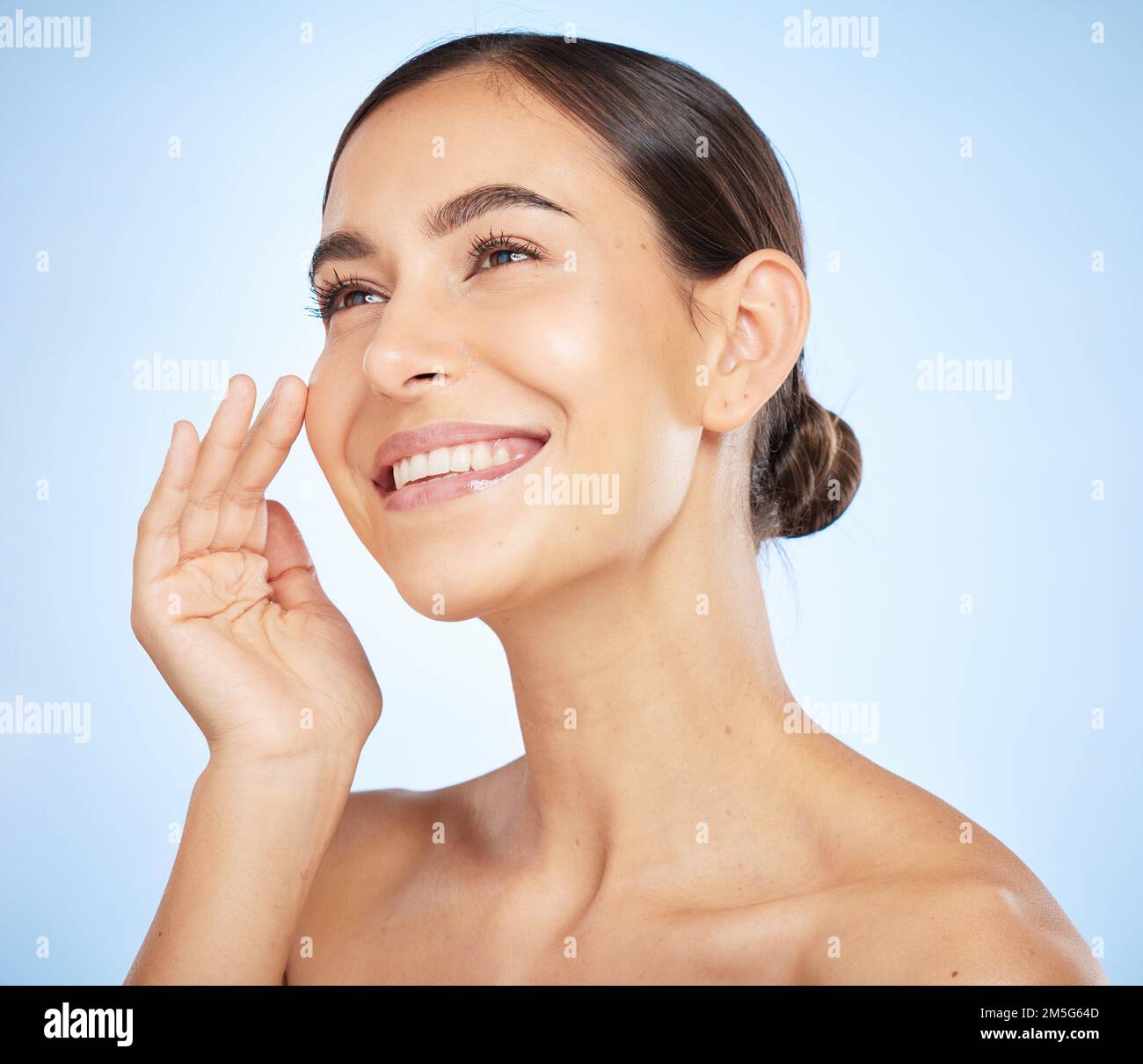 Face, beauty and skincare with a model woman in studio on a blue ...