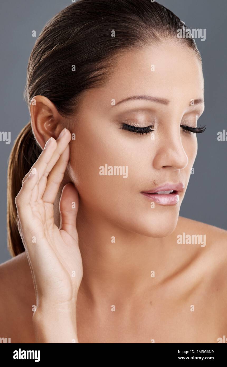 Treating her skin with tender loving care. a beautiful young woman posing in the studio Stock ...