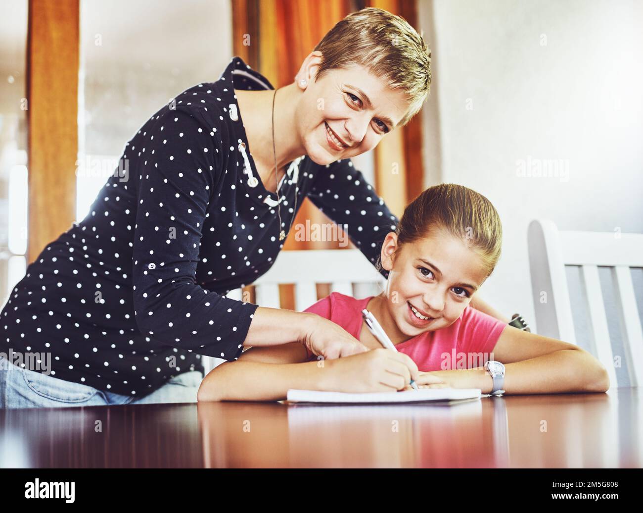 Doing homework together. Portrait of a cheerful mother and daughter doing homework together ...
