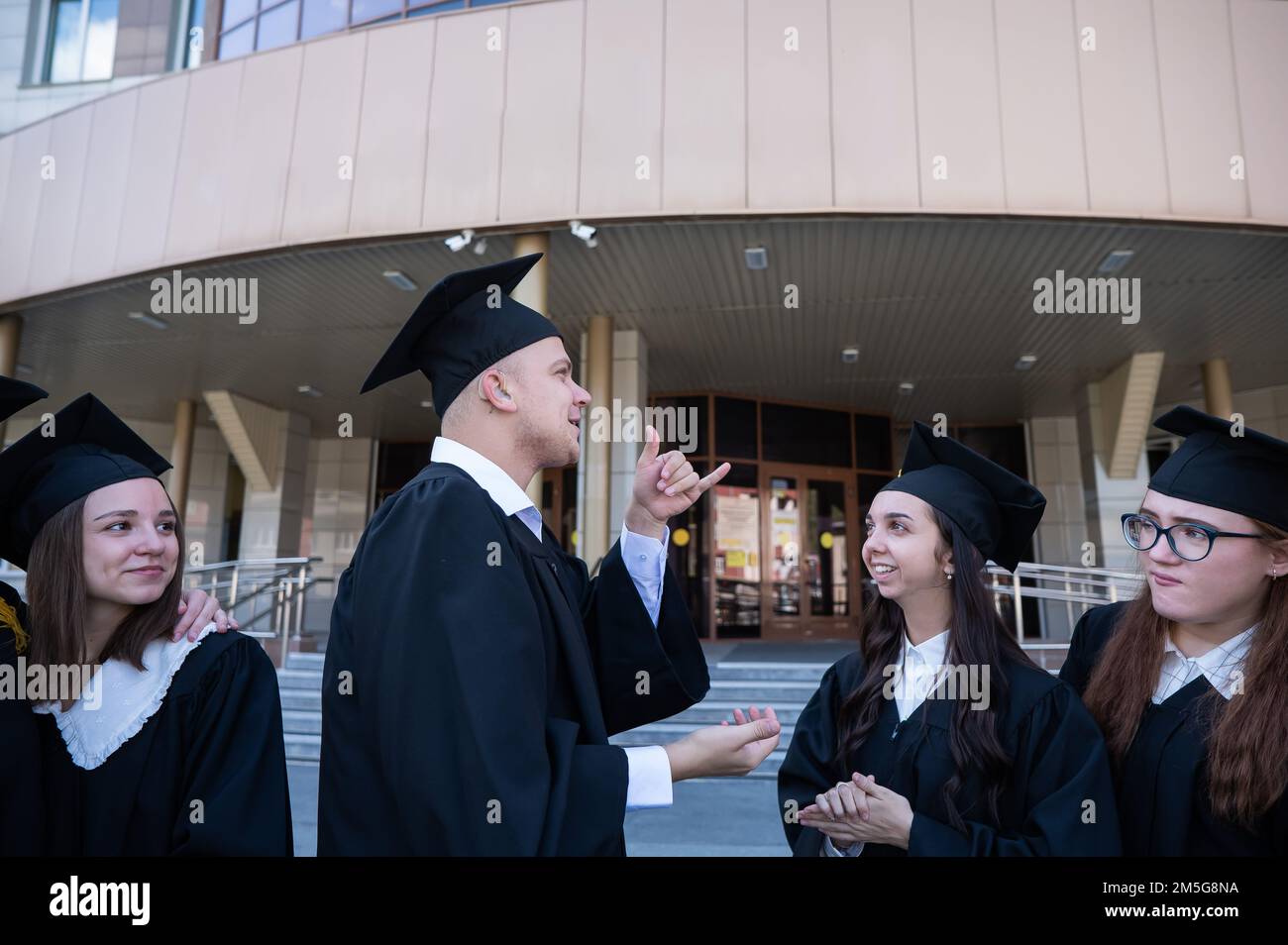 Happy students in graduate gown communicate in sign language Stock ...