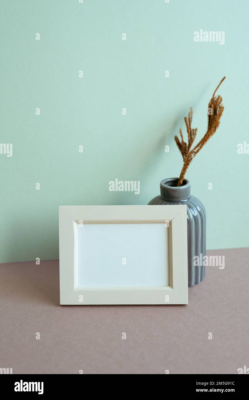 Blank picture frame and vase of dry plant on table. mint wall ...