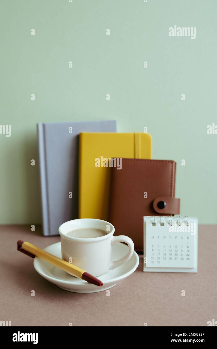 Diary notebook, calendar, pen, cup of coffee on desk. mint wall ...