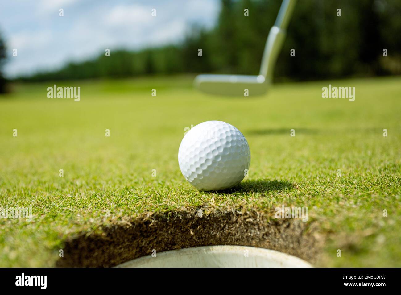 Hole on the golf course, next to a white ball Stock Photo - Alamy
