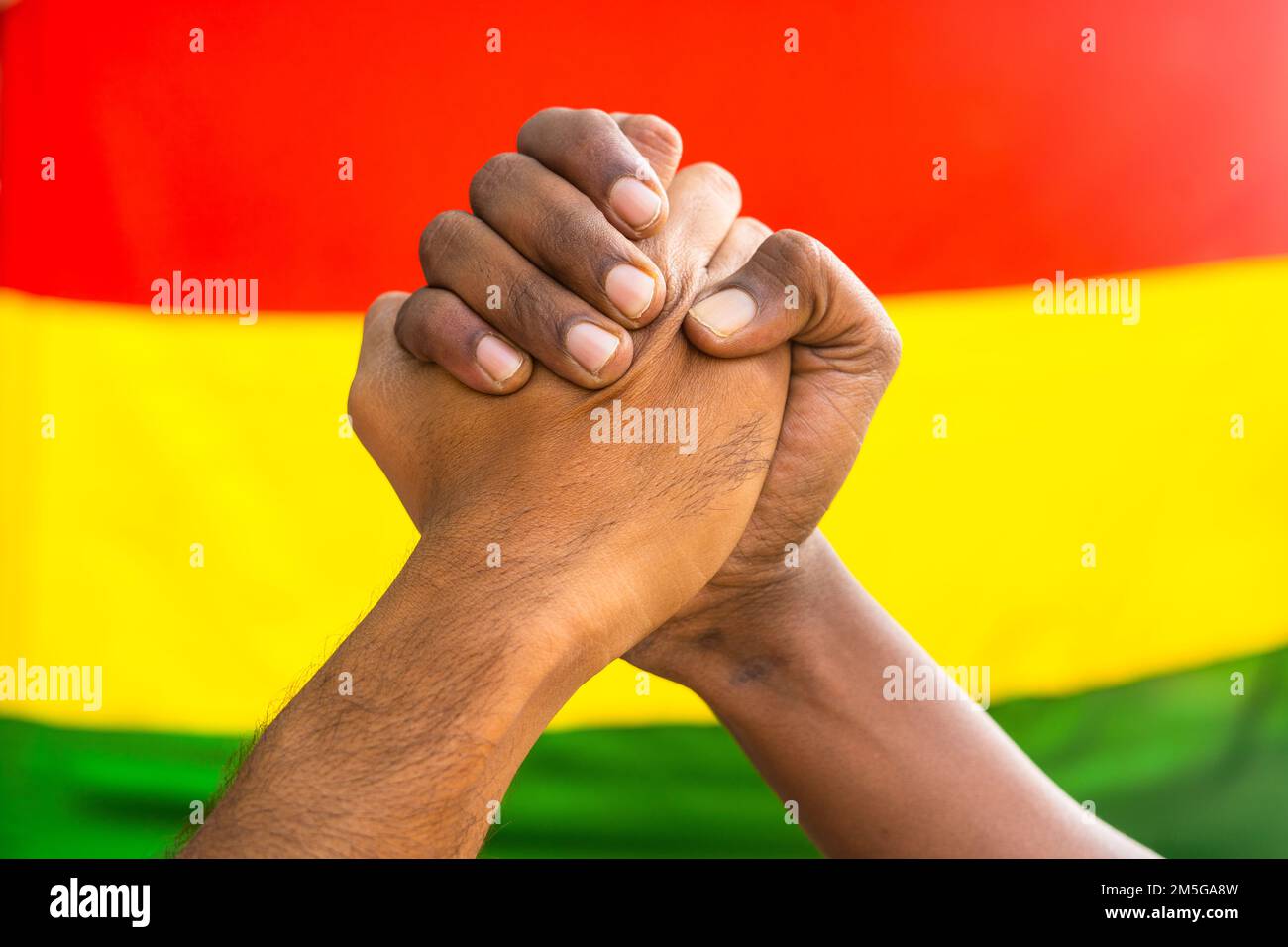 Two diverse hands joining hands against black history month flag to ...
