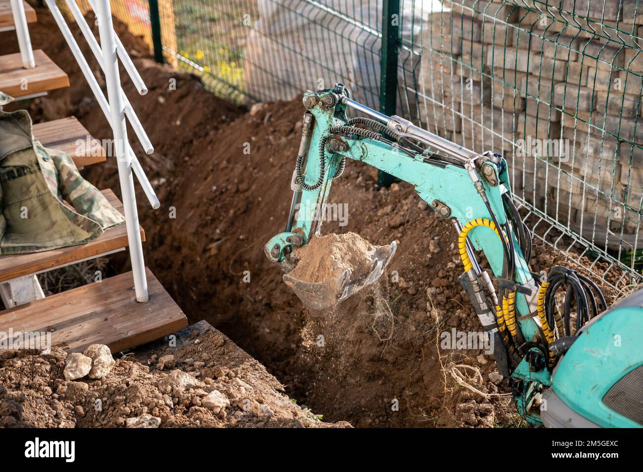 Mini excavator digs a trench to lay pipes. Close up of an excavator ...