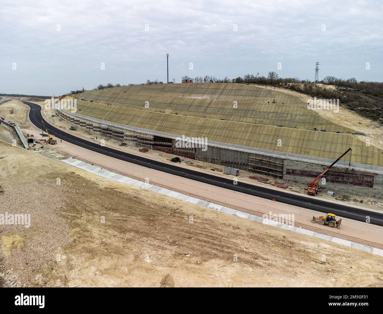 Mountain road constraction. Workers reinforce the slope over the new ...