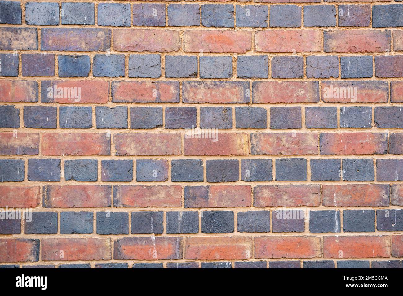 Brick wall with alternate red and black courses Stock Photo - Alamy