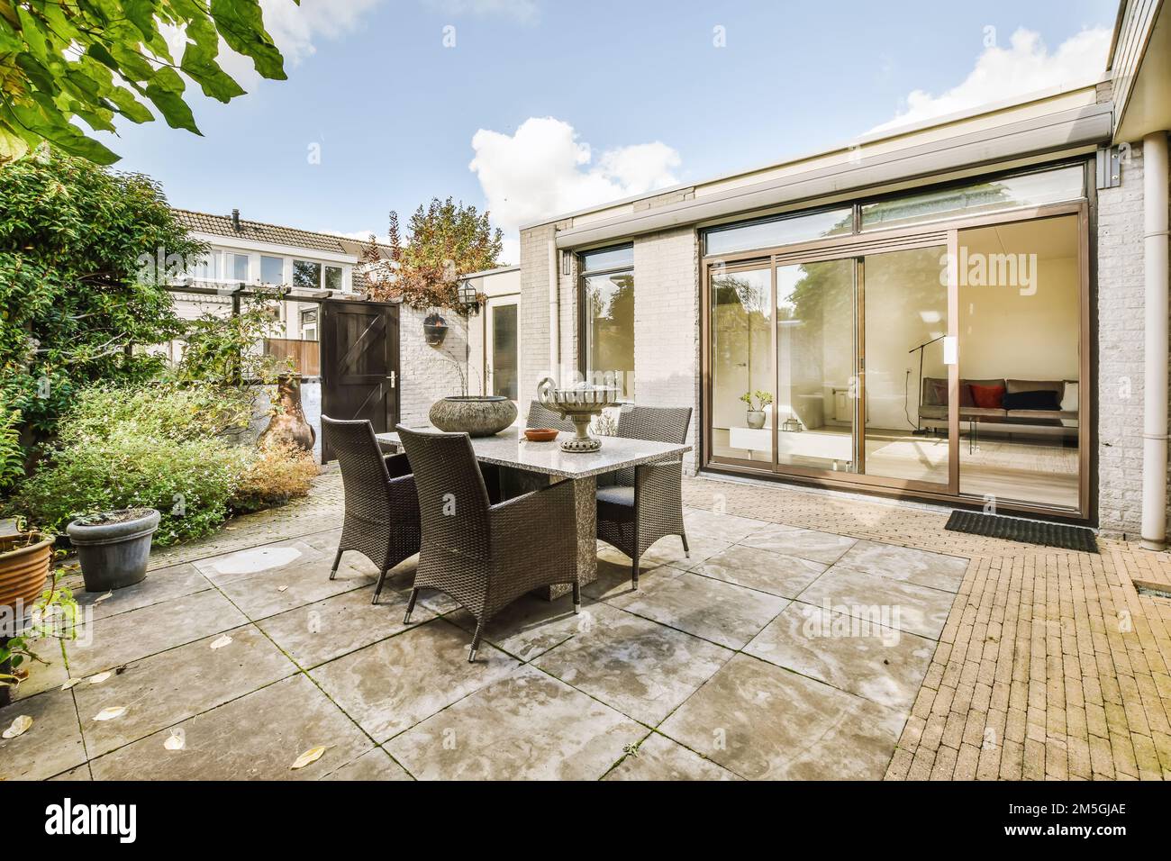 a patio with chairs, table and pots on the ground in front of an open ...