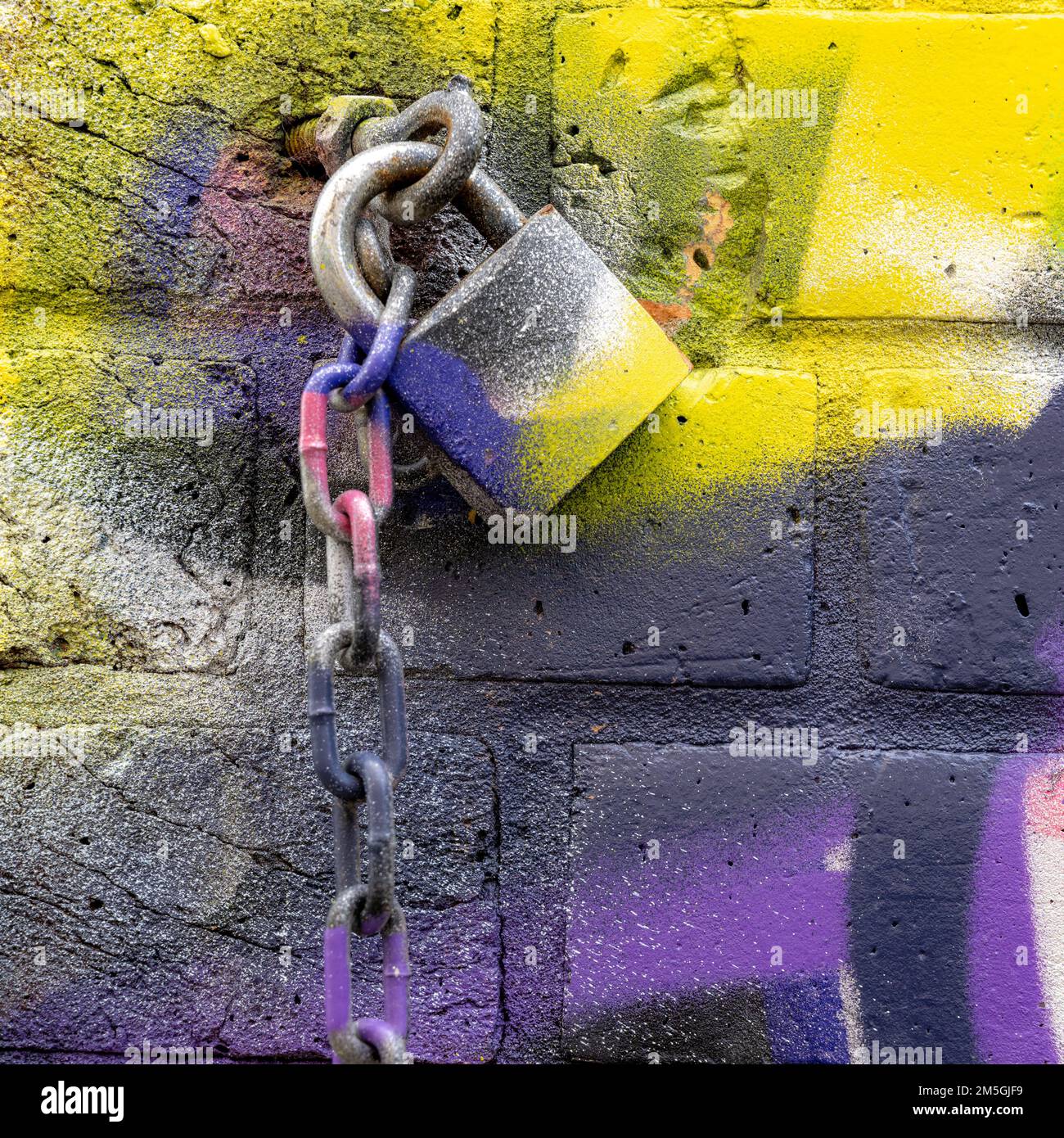 Padlock and chain hanging on a grafittied brick wall Stock Photo - Alamy