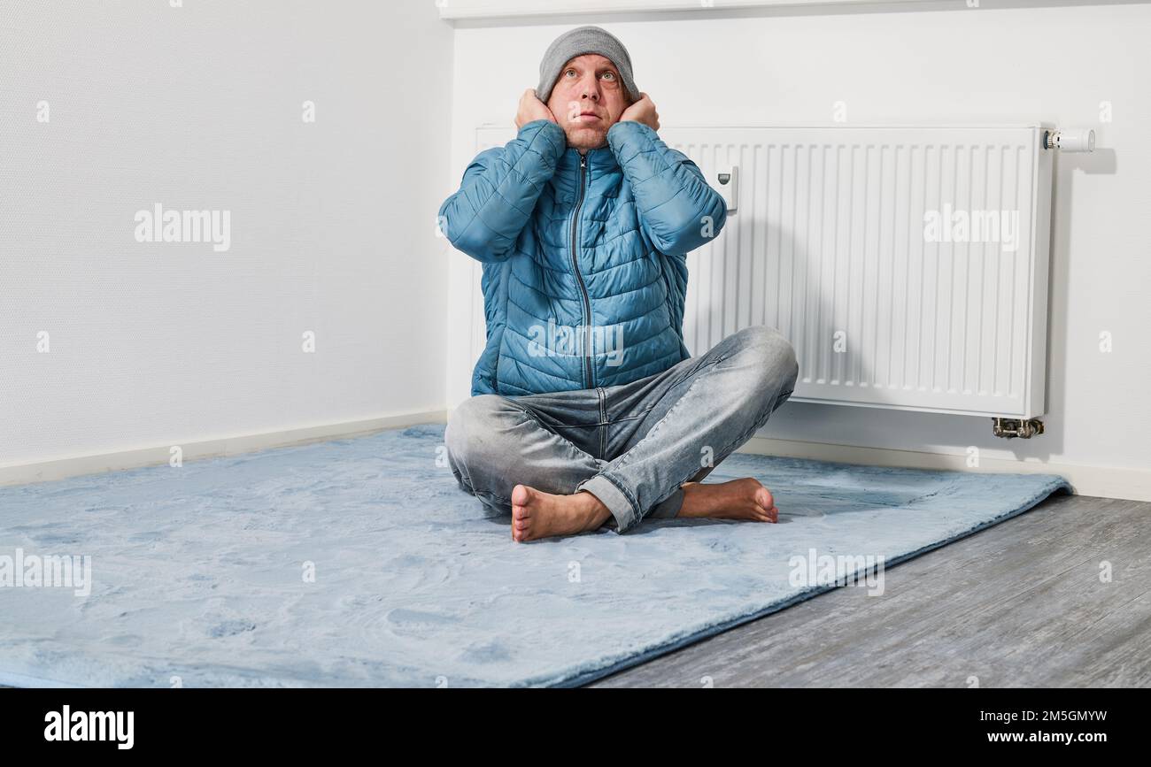 Man freezing in front of heating radiator Stock Photo - Alamy