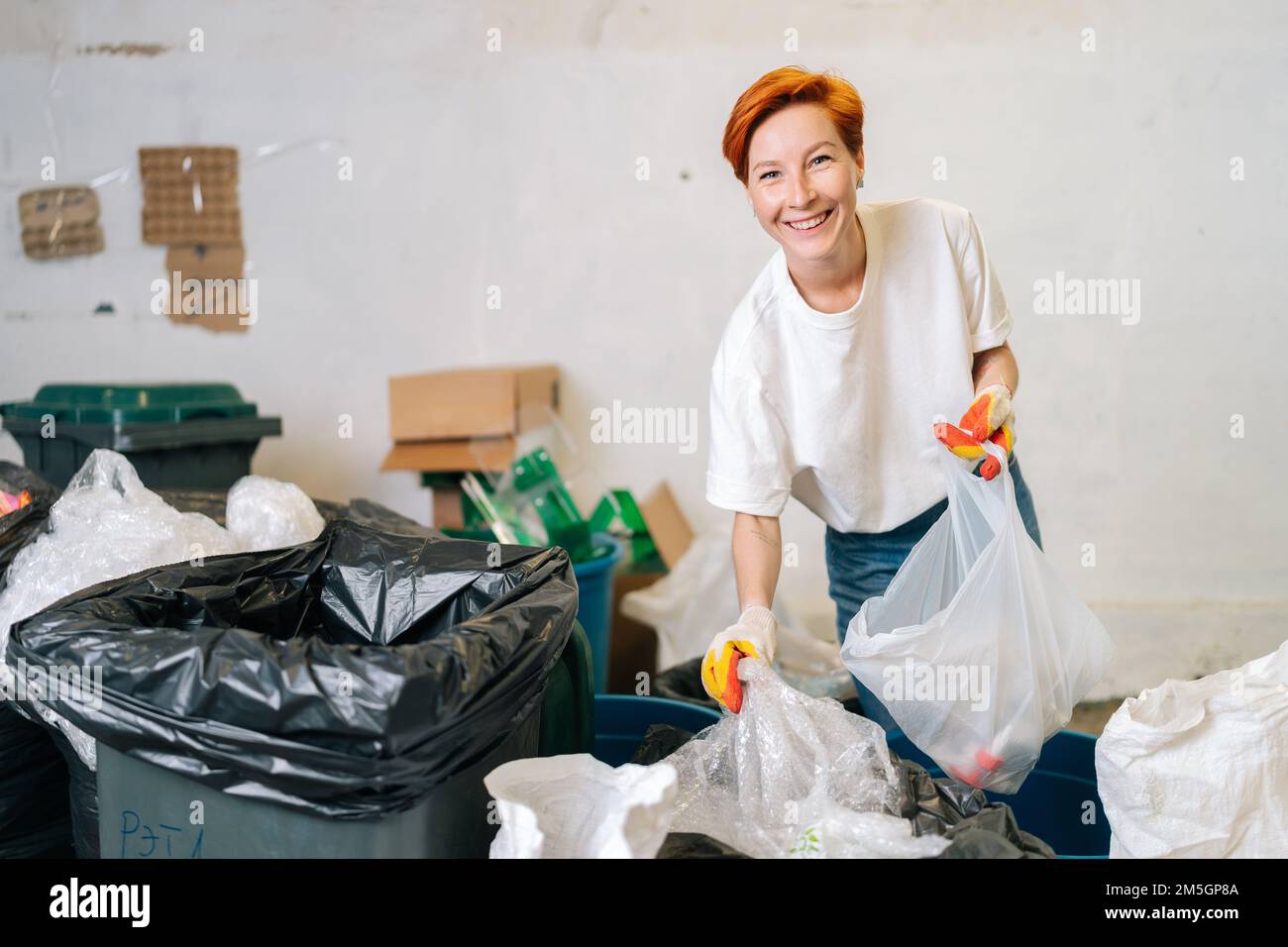 Positive redhead young woman worker wearing latex gloves sorting ...
