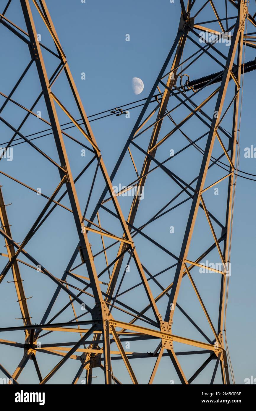 A vertical shot of the moon shining behind the transmission tower ...