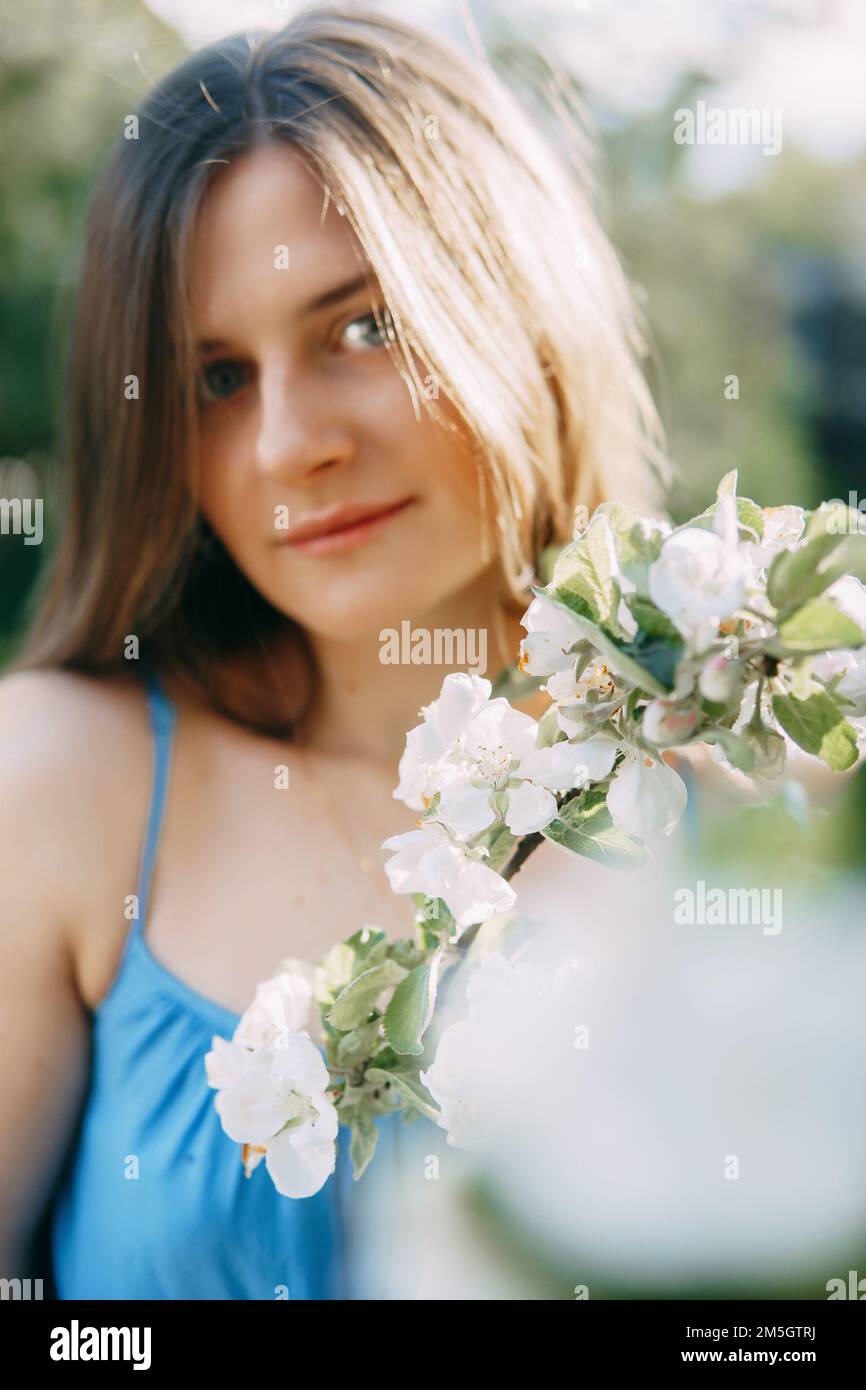 Beautiful young girl in a blue dress in a blooming Apple orchard ...