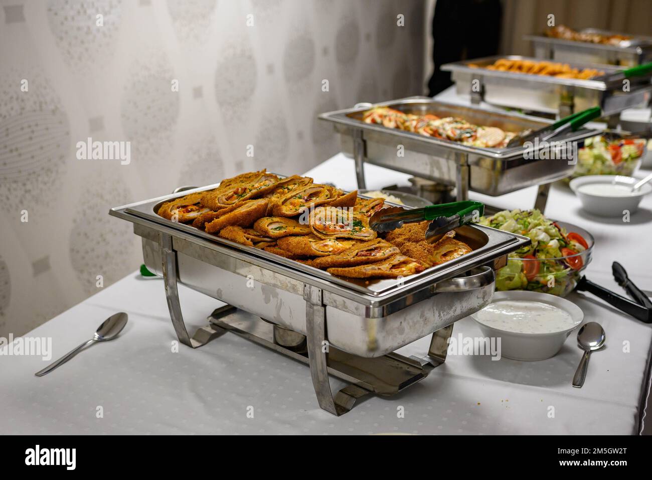 A buffet full of different dishes such as salads and cutlets on metal ...