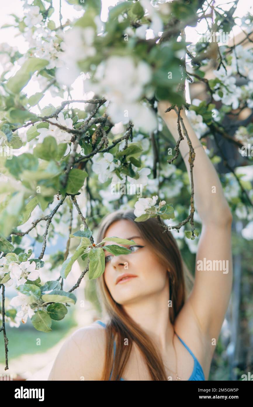 Beautiful young girl in a blue dress in a blooming Apple orchard ...