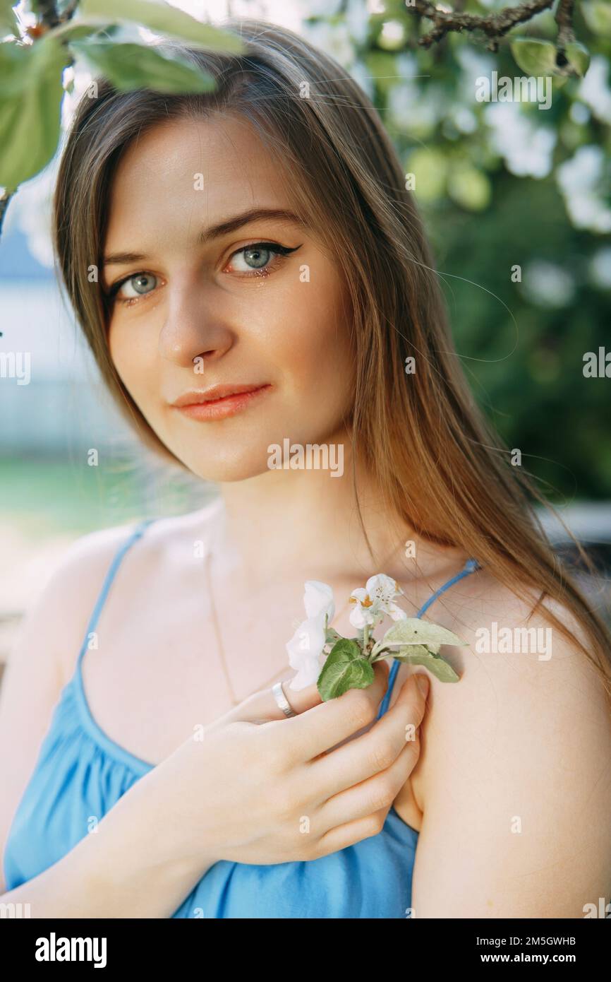 Beautiful young girl in a blue dress in a blooming Apple orchard ...