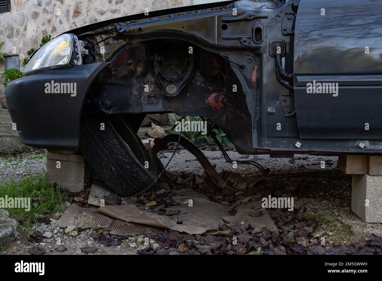 Close-up of a dark car without wheel, held in place with cement blocks ...