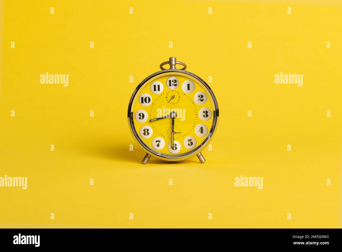 Round yellow alarm clock on a bright yellow background with space for ...