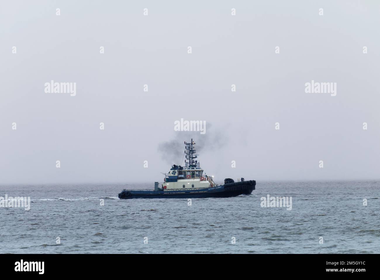 Tug with black smoke coming out of the funnel Stock Photo - Alamy