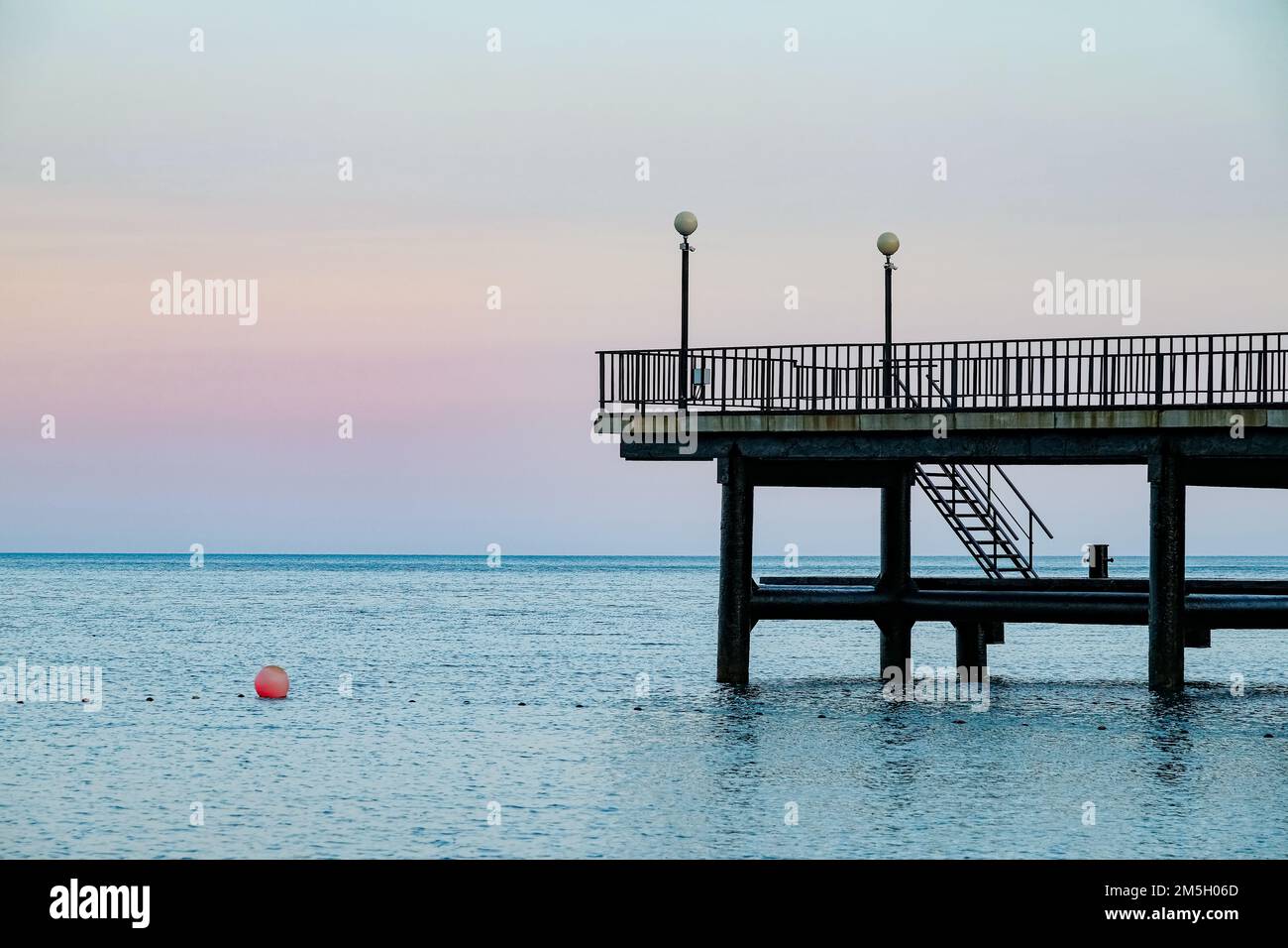 A seascape view of a wooden fishing pier extending into the foamy waves ...