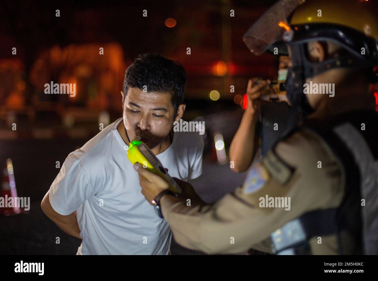 A thai police officer takes a driver through an alcohol tests using a ...