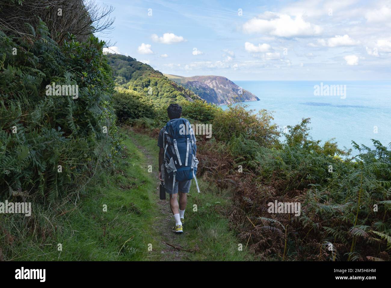Hiker walks along the south west coast path towards Lynmouth, Devon ...