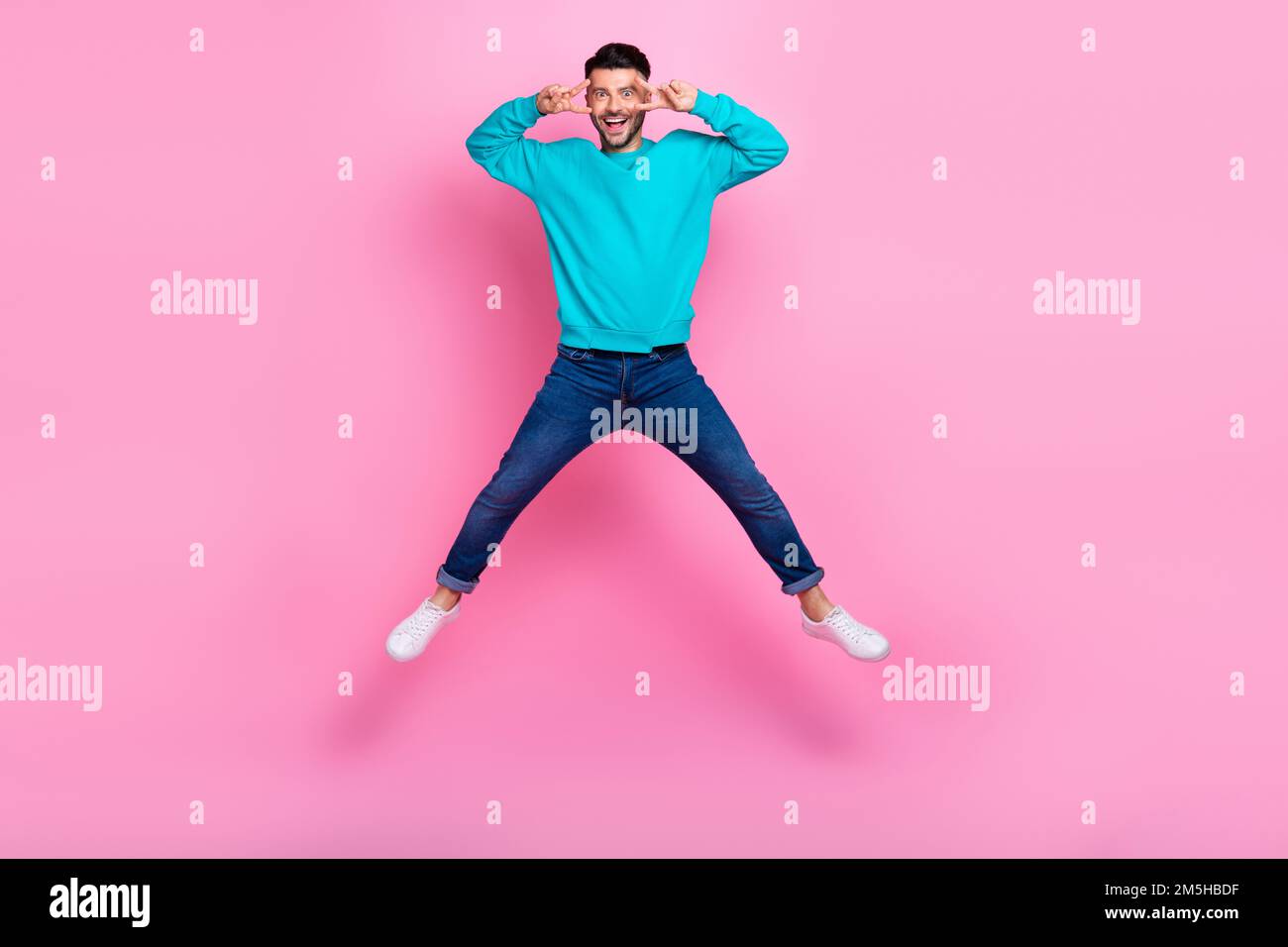 Full length photo of young handsome male jumping showing v-sign spread ...