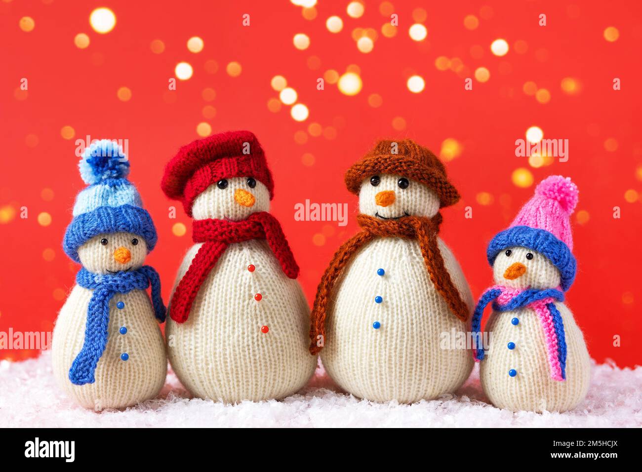 Family of knitted snowmen celebrate the holidays on a red background ...