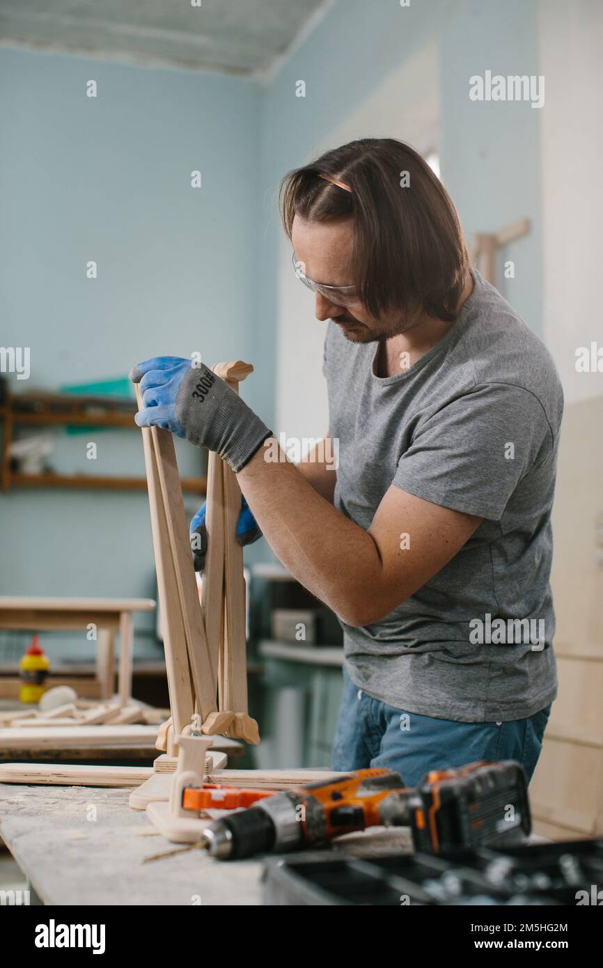 A carpenter makes wooden toys in a carpentry workshop. Making a bed ...