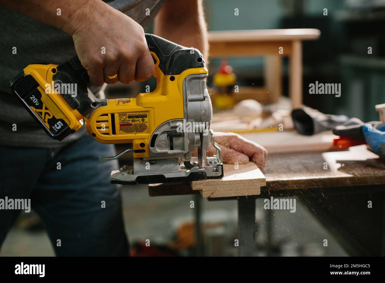 Close up on hand of unknown carpenter working with an electric jigsaw ...