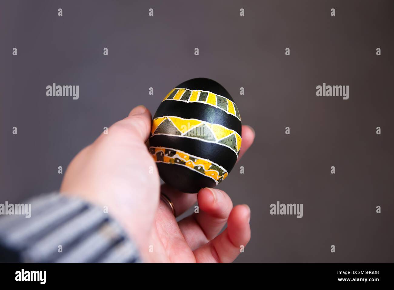 Defocus Easter black and yellow egg in female hand. Close up Easter ...