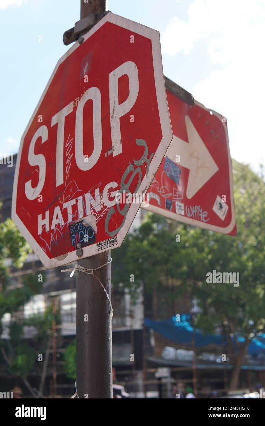 A vertical closeup shot of a red 'stop hating' sign and an arrow on a ...
