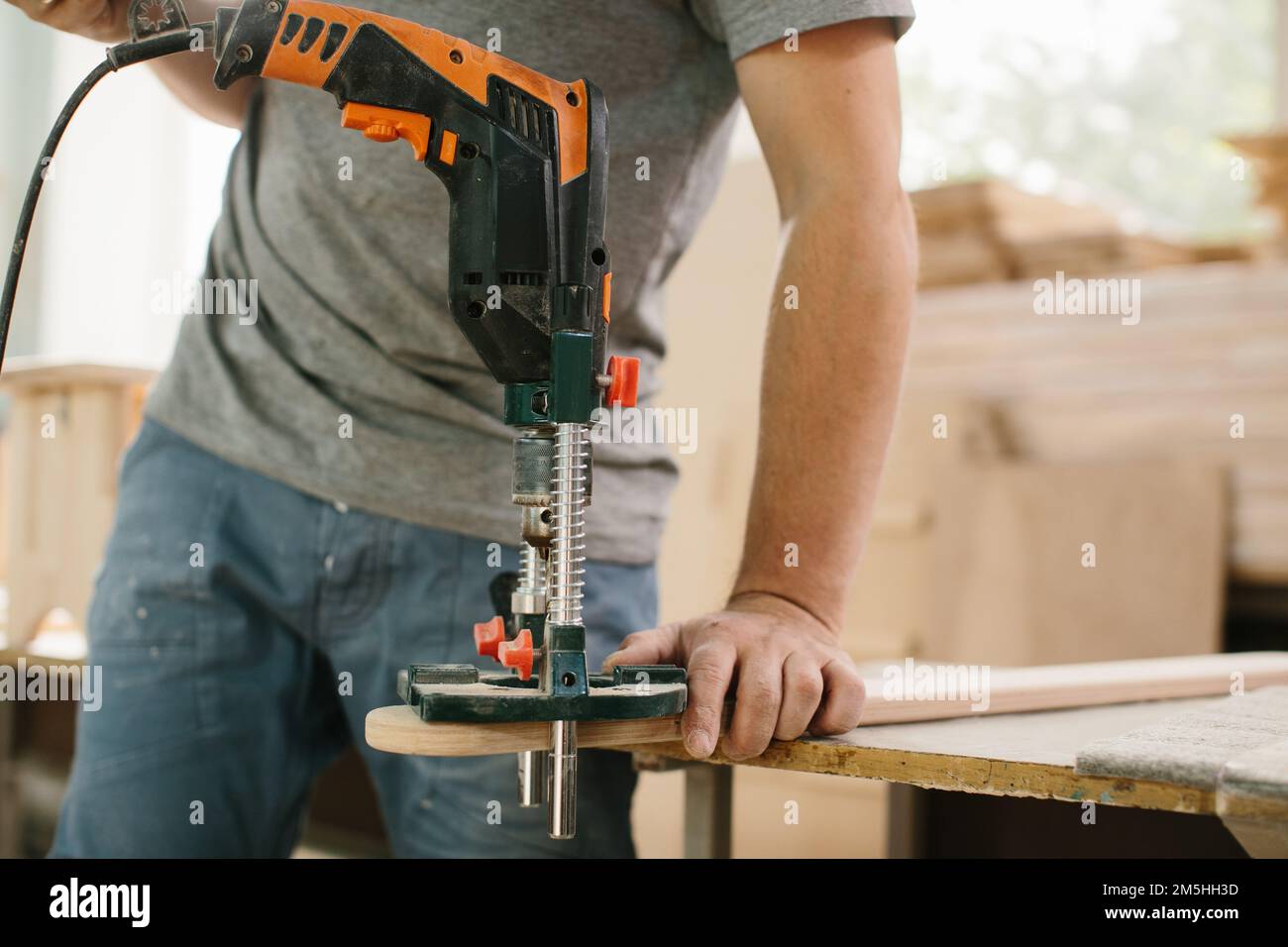 The master works in a studio and drill a hole in a wooden board Stock ...