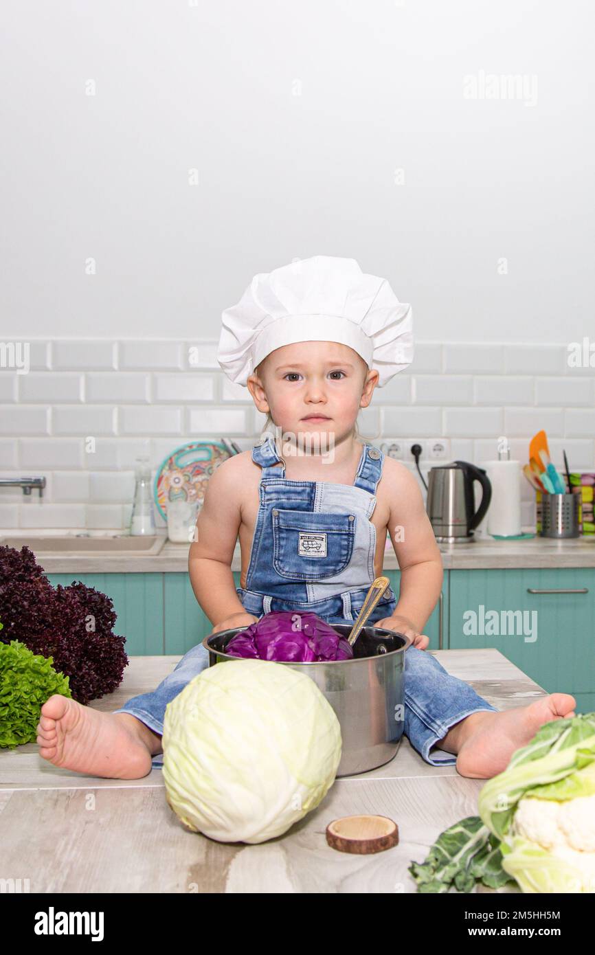 A cute little boy in a chef's costume cooks food with emotions. High ...