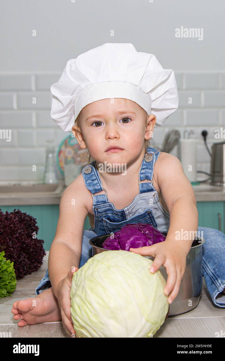 A cute little boy in a chef's costume cooks food with emotions. High ...
