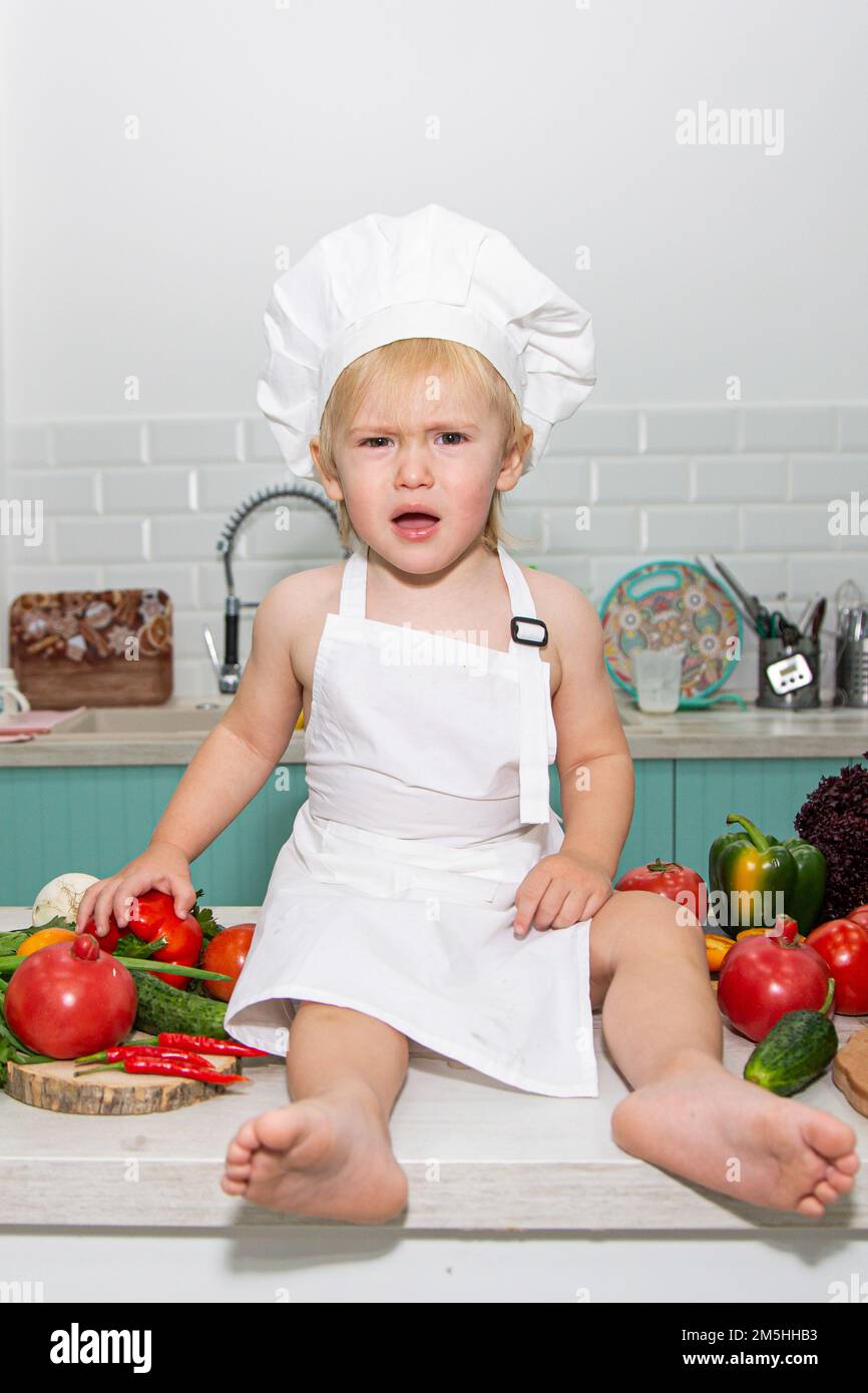 A cute little boy in a chef's costume cooks food with emotions. High ...