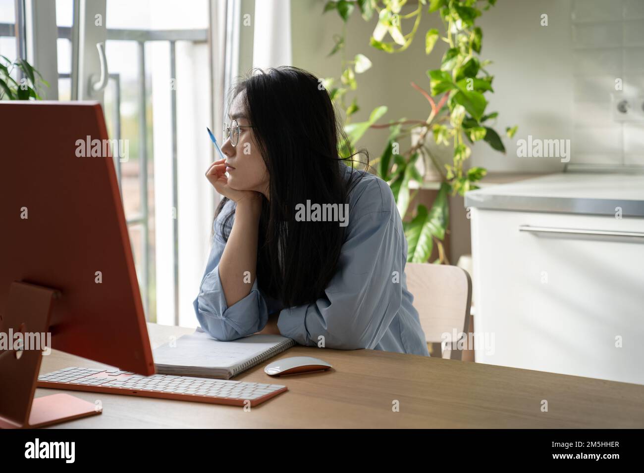 Unmotivated lazy girl sits at desk with computer and looks out window ...