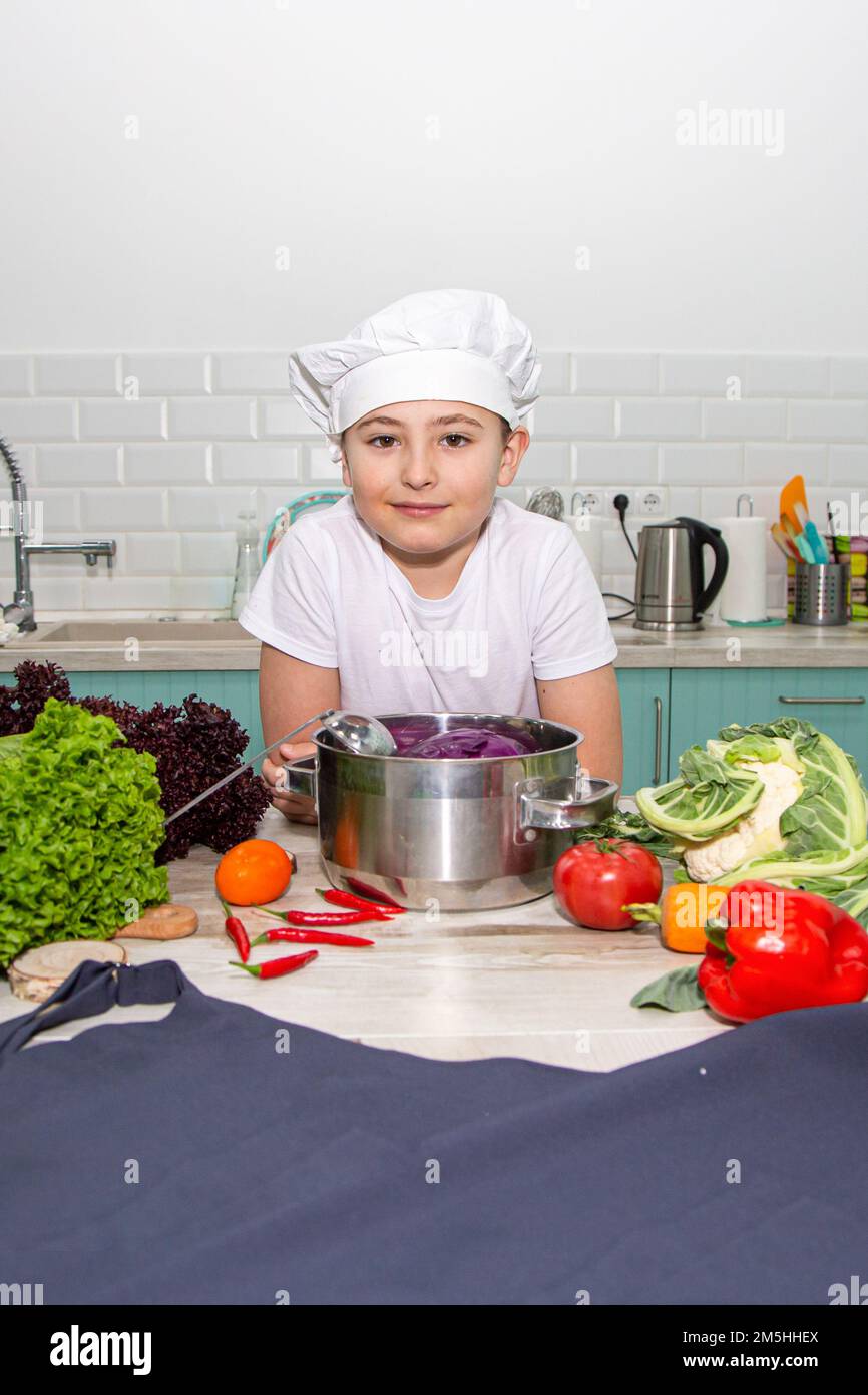 A cute little boy in a chef's costume cooks food with emotions. High ...