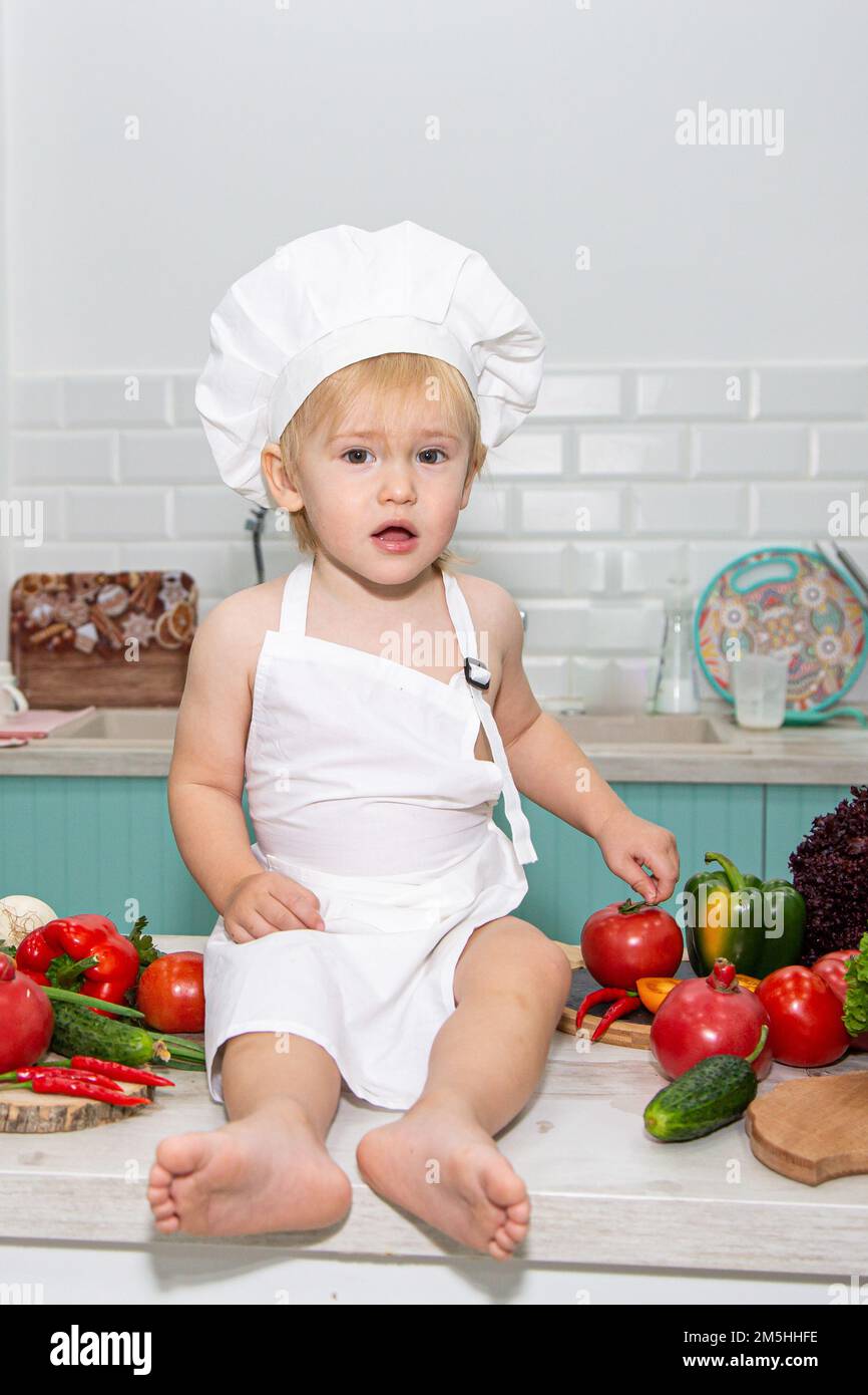 A cute little boy in a chef's costume cooks food with emotions. High ...