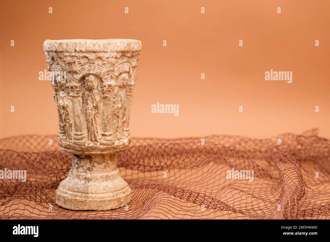 stone chalice with fishing net on a brown background Stock Photo - Alamy