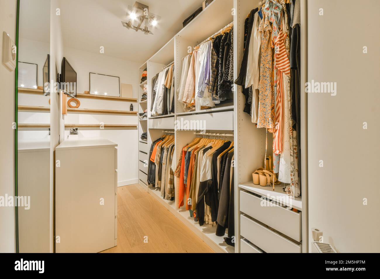 a walk - in closet with lots of clothes hanging on the wall, and an ...