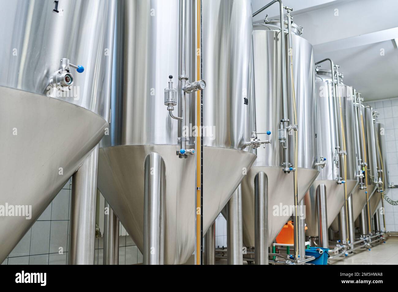 Stainless steel tanks for brewing drinks standing in a row in storage ...