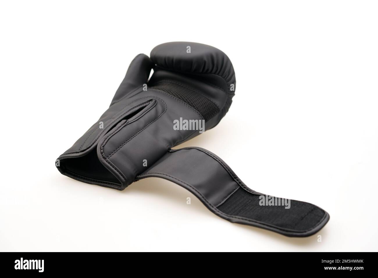 A single black boxing glove with an open strap isolated on a white ...