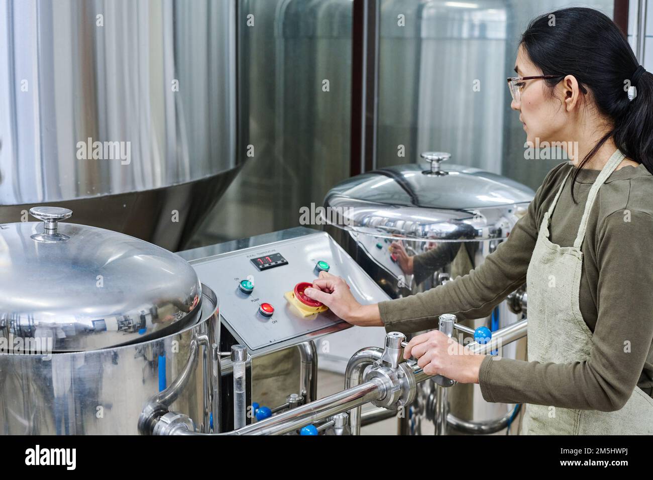 Female worker standing in front of control panel and pushing the button ...