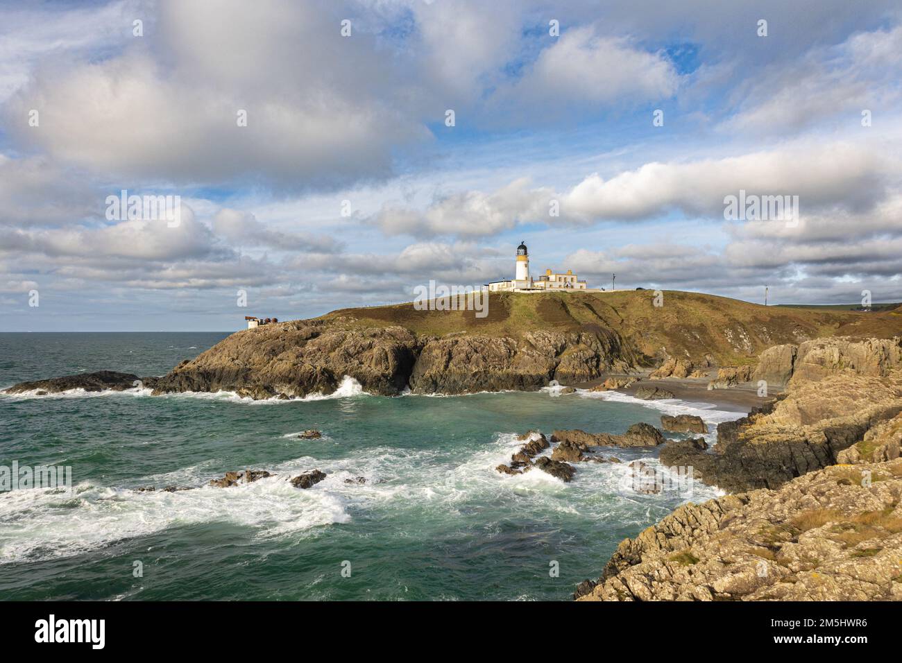 A lighthouse on top of a cliff surrounded by the calm sea against the ...
